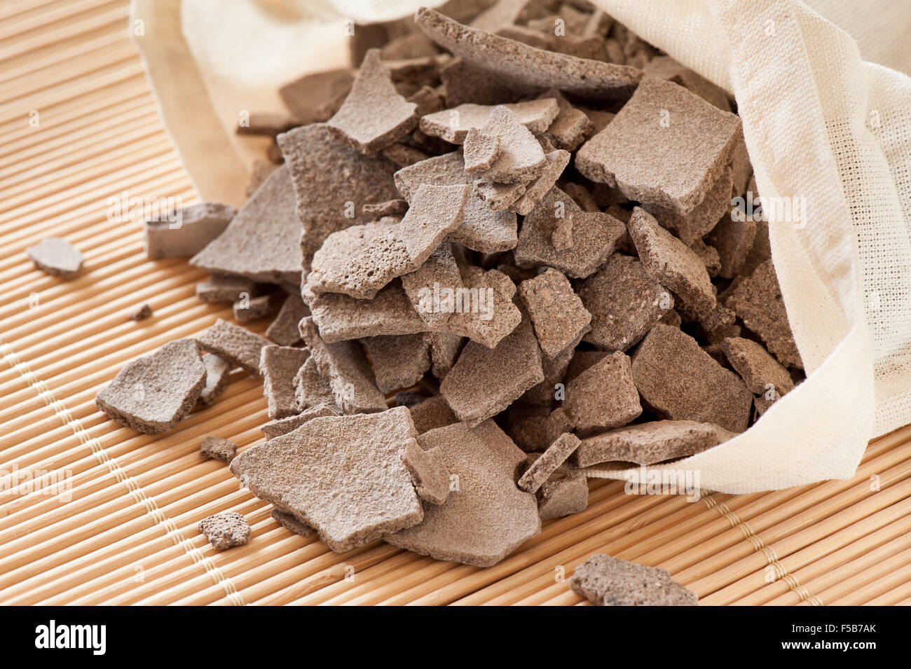 Rhassoul Moroccan lava clay dried chips mud spilled out of cloth bag on ...