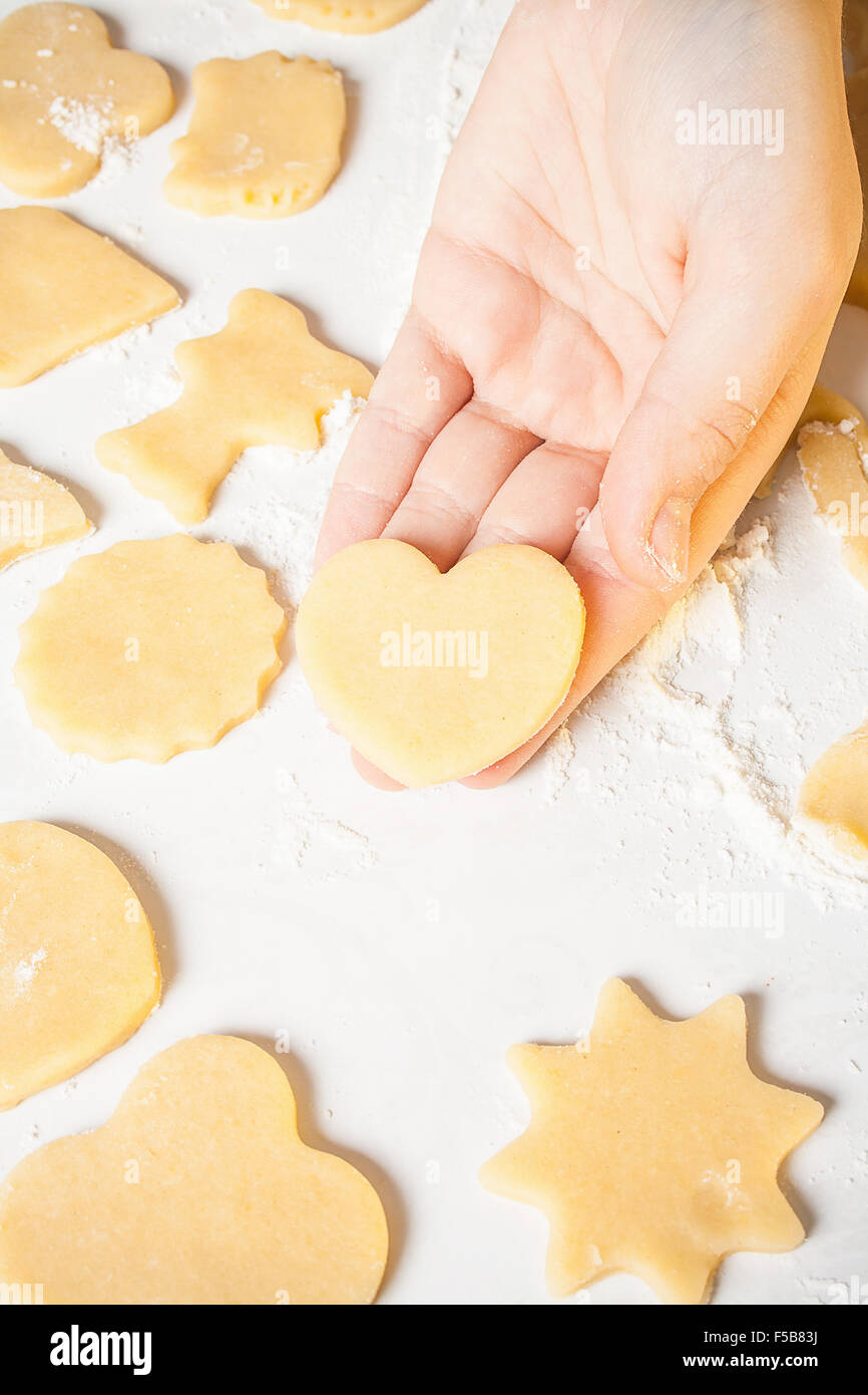 Girl shows heart shape out of dough, top view Stock Photo - Alamy