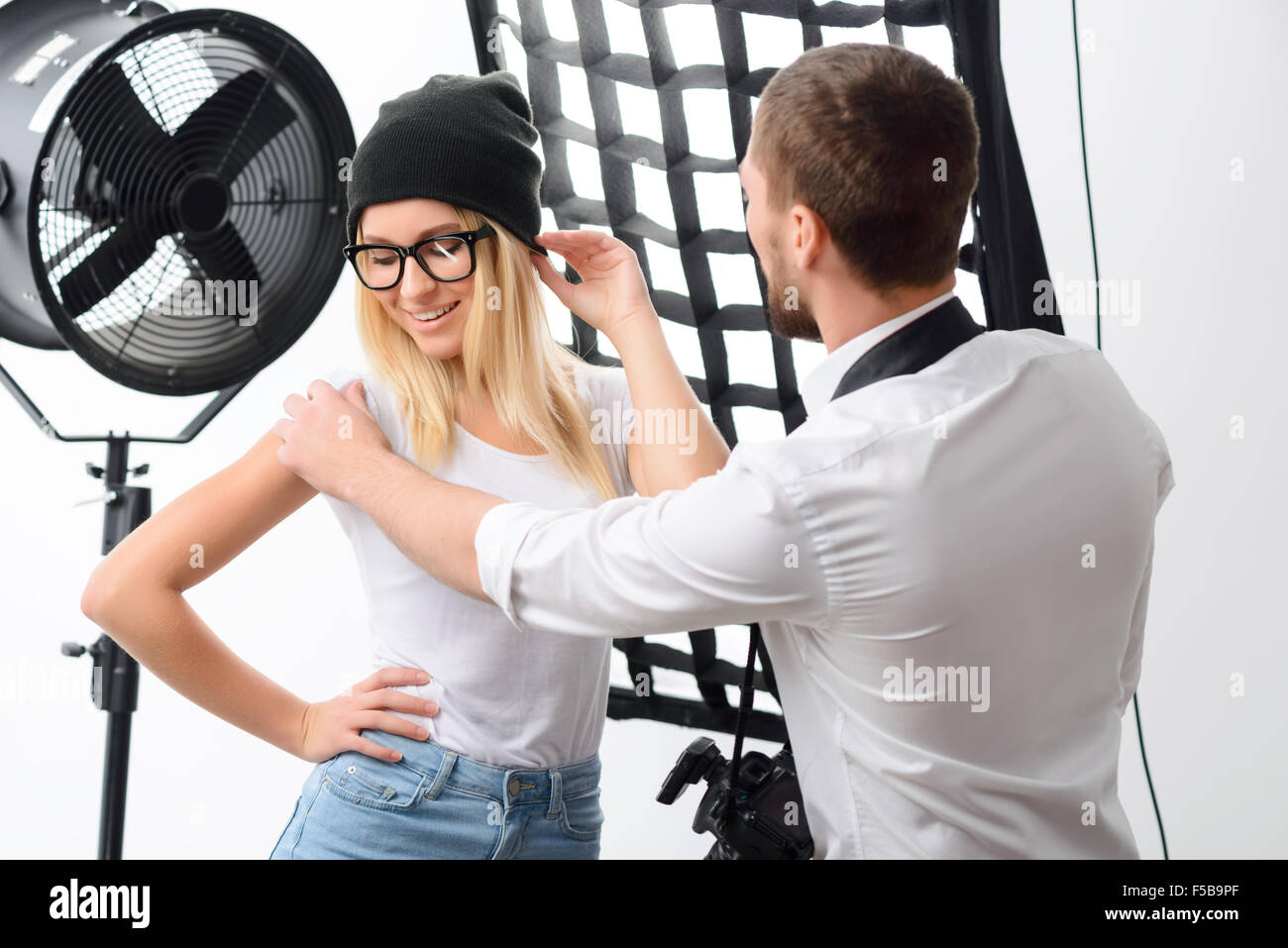 Cameraman adjusts posture of young model Stock Photo - Alamy