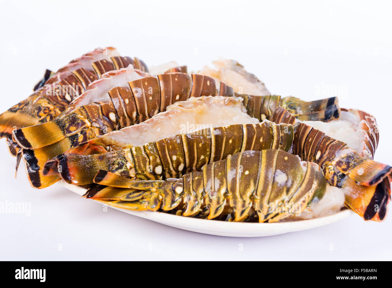Raw lobster tails on a white plate ready to cook Stock Photo - Alamy