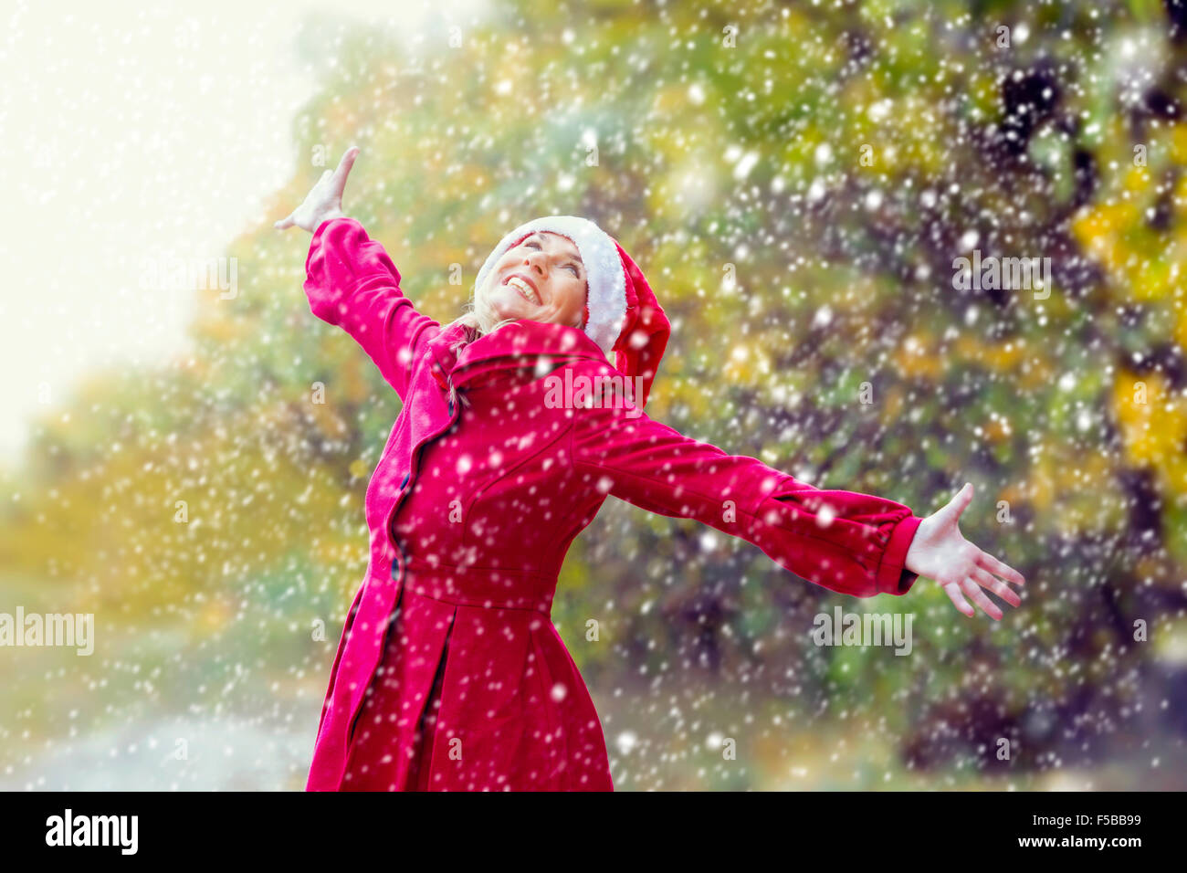 woman in Santa hat standing outside and enjoying the first snowfall ...