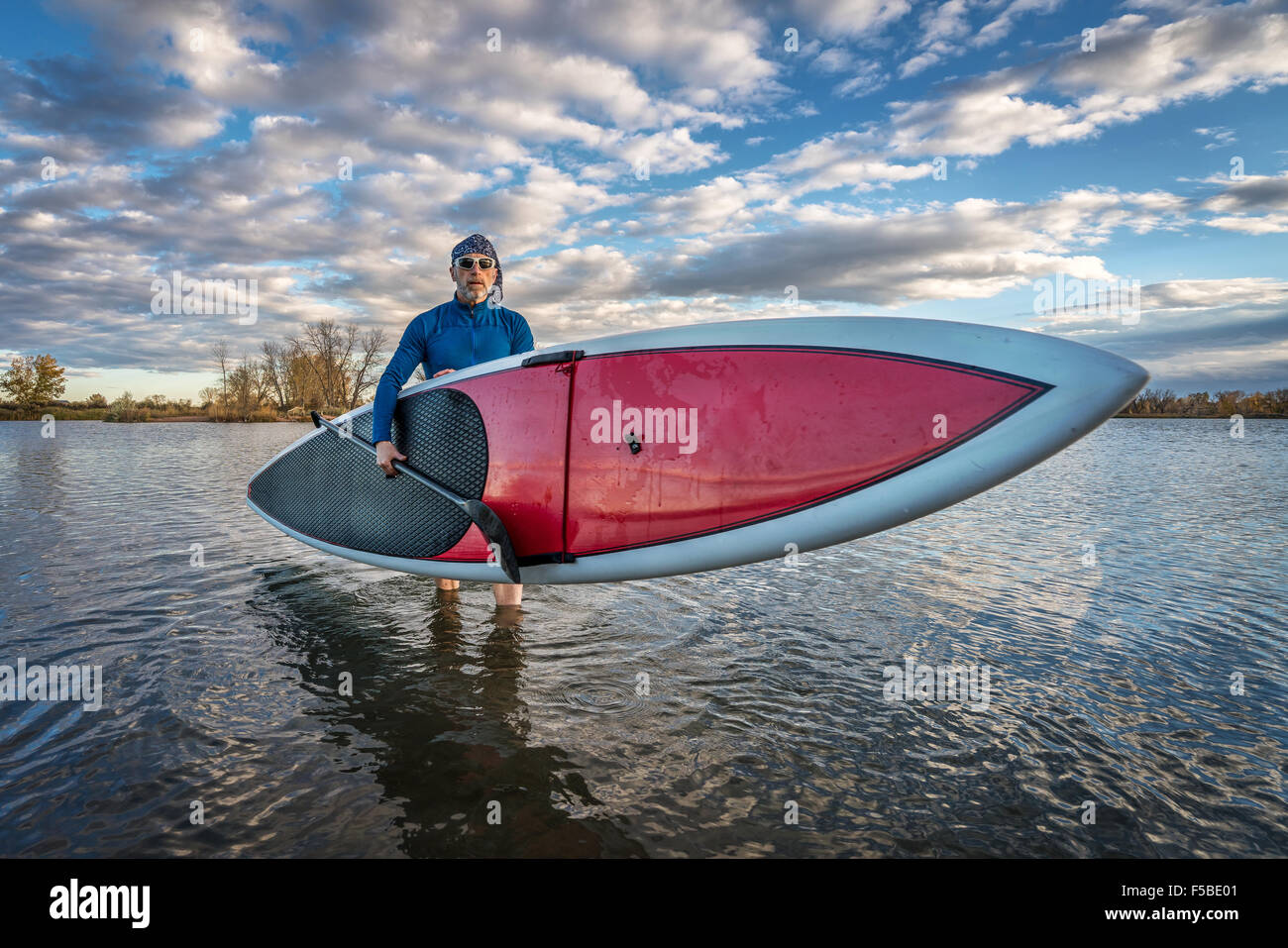 senior male launching his 14 feet long expedition stand up paddleboard ...