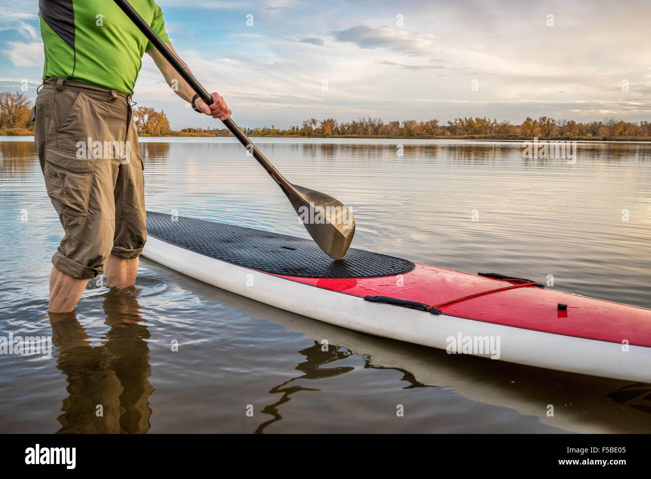 male paddler is starting paddling workout on his stand up paddleboard ...