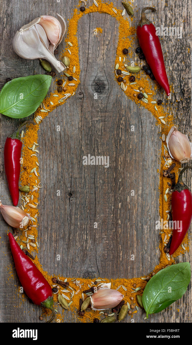 chili, garlic, basil, star anise and spices on a wooden background ...