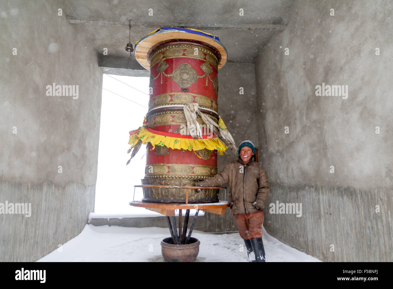 A Ladakhi boy spinning a big prayer wheel at the Korzok village Stock ...