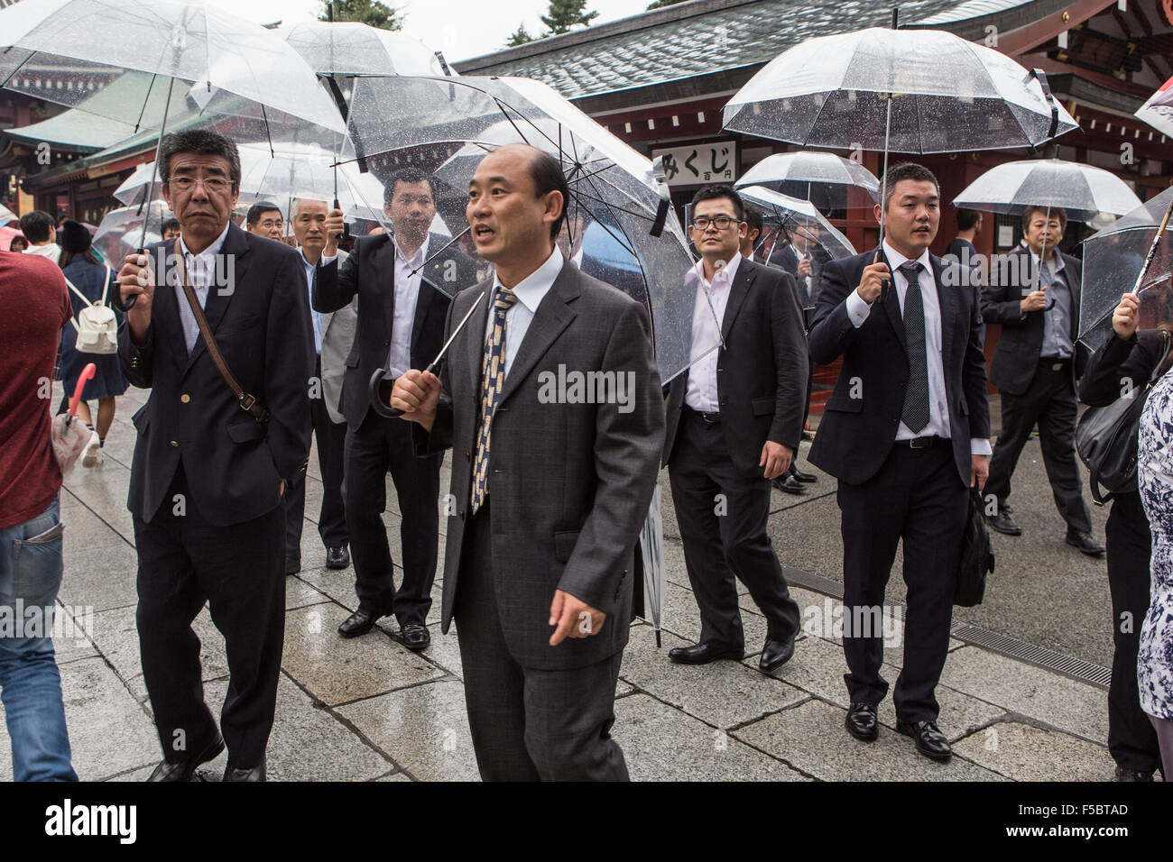 A group of Japanese businessmen wearing suits and holding see through ...