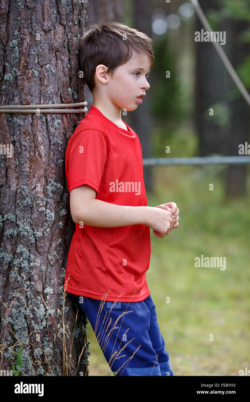 Sad little boy standing under the tree Stock Photo - Alamy