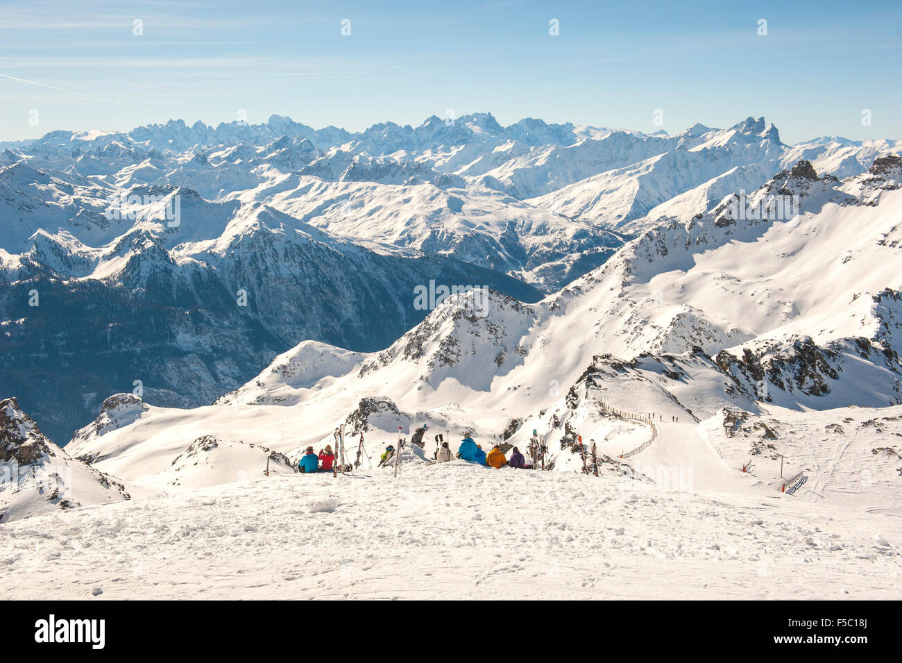 View over an alpine mountain range with skiers relaxing on the slope ...