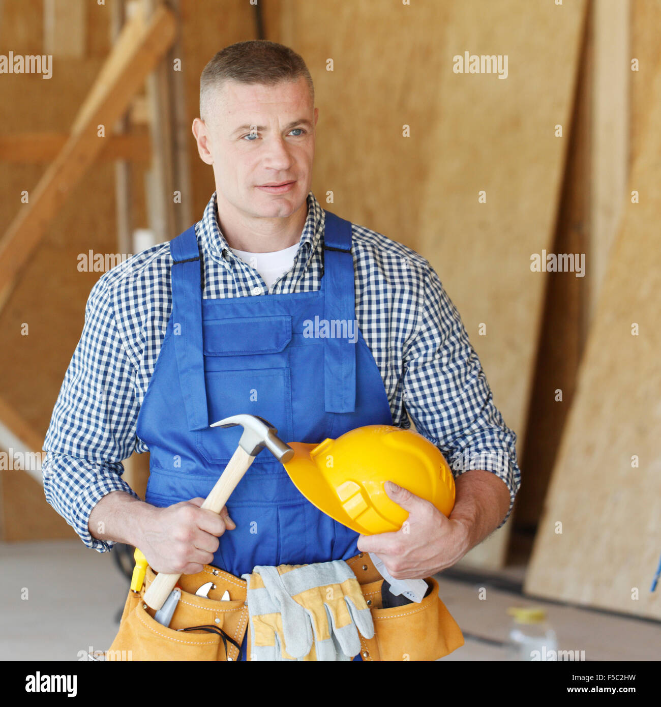 Handyman with hammer and protective helmet in house under construction ...