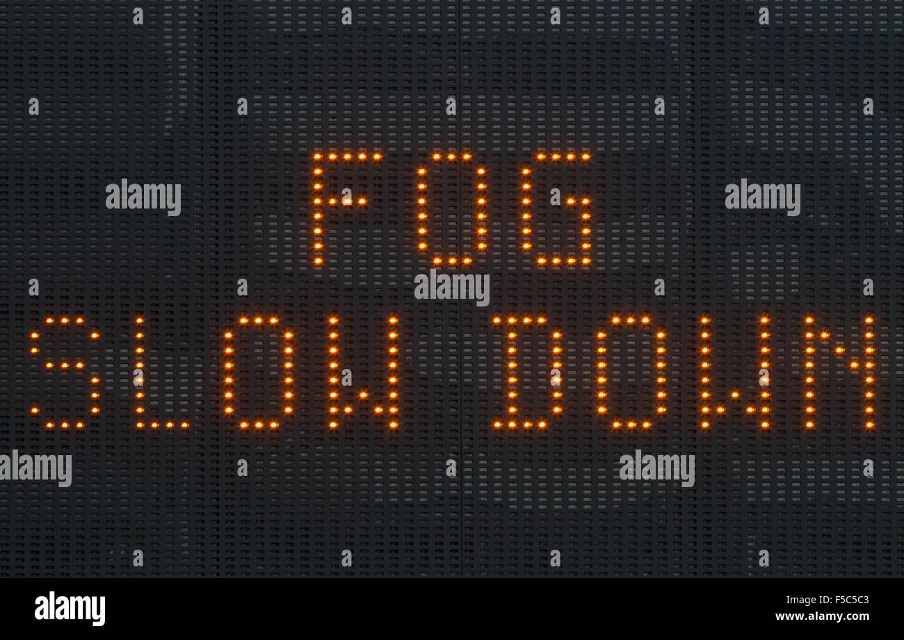 An illuminated motorway matrix sign which reads 'FOG SLOW DOWN' on the ...