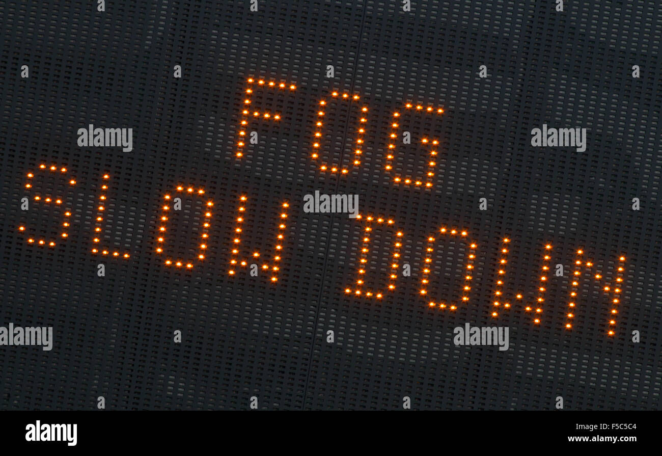 An illuminated motorway matrix sign which reads 'FOG SLOW DOWN' on the ...