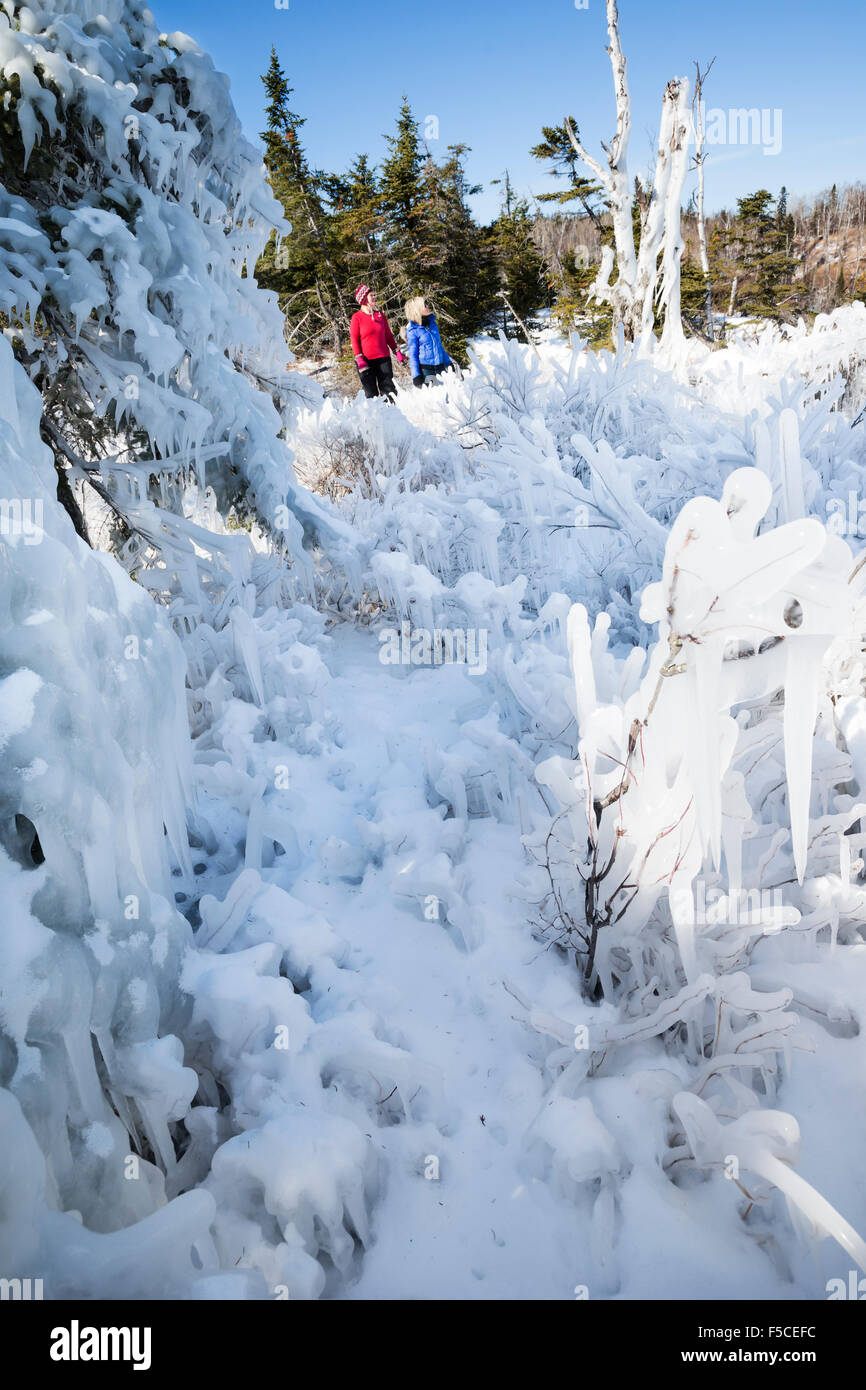 Two people admire the frozen forest along Lake Superior in the winter ...
