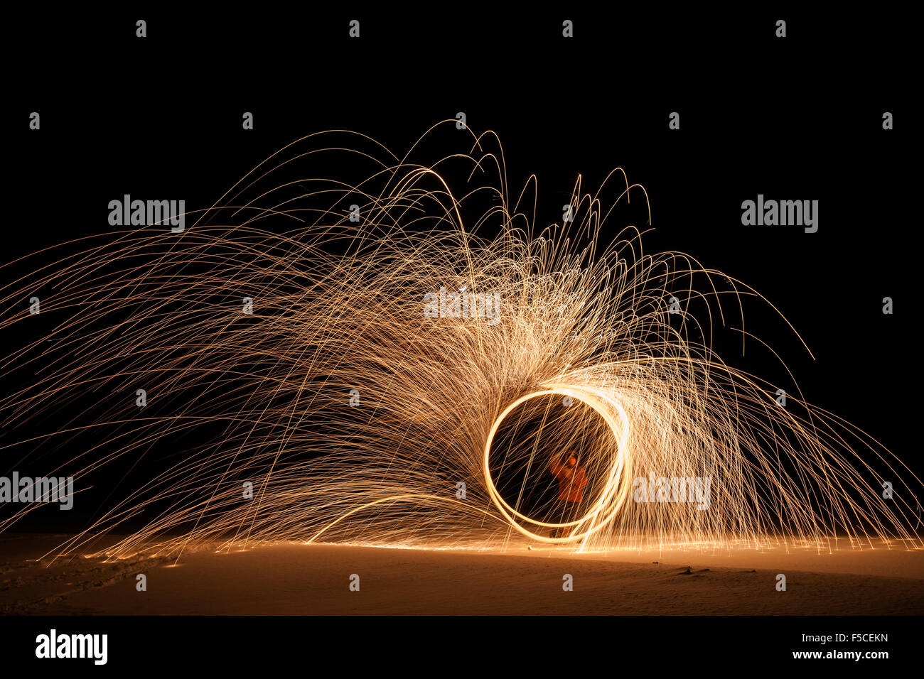Light painting at night created by man whirling steel wool burning at ...