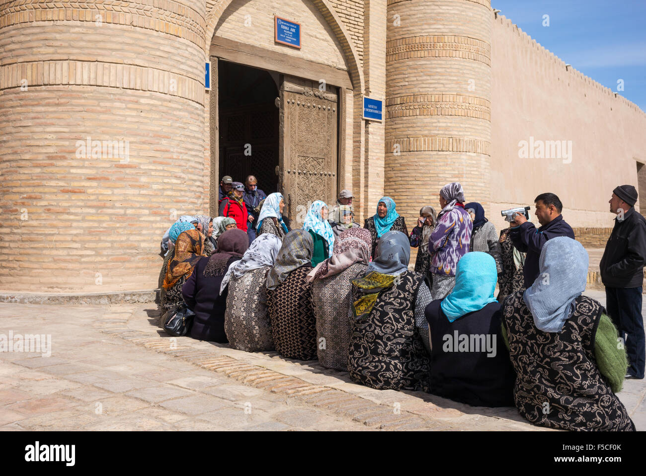 Uzbekistan, Khiva, local people seated near the gate of the Ichan Kala ...