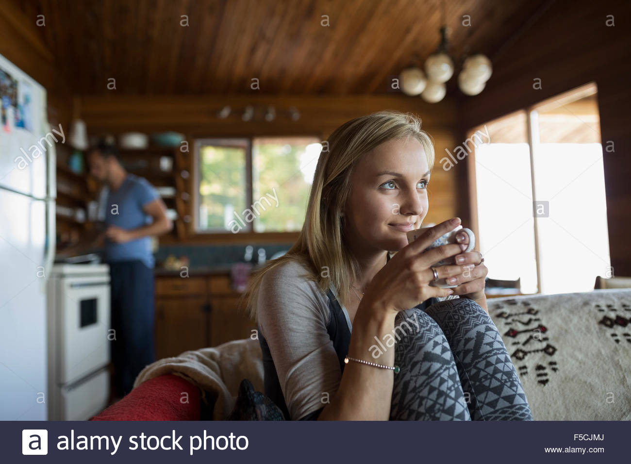 Young woman drinking coffee on cabin sofa Stock Photo - Alamy