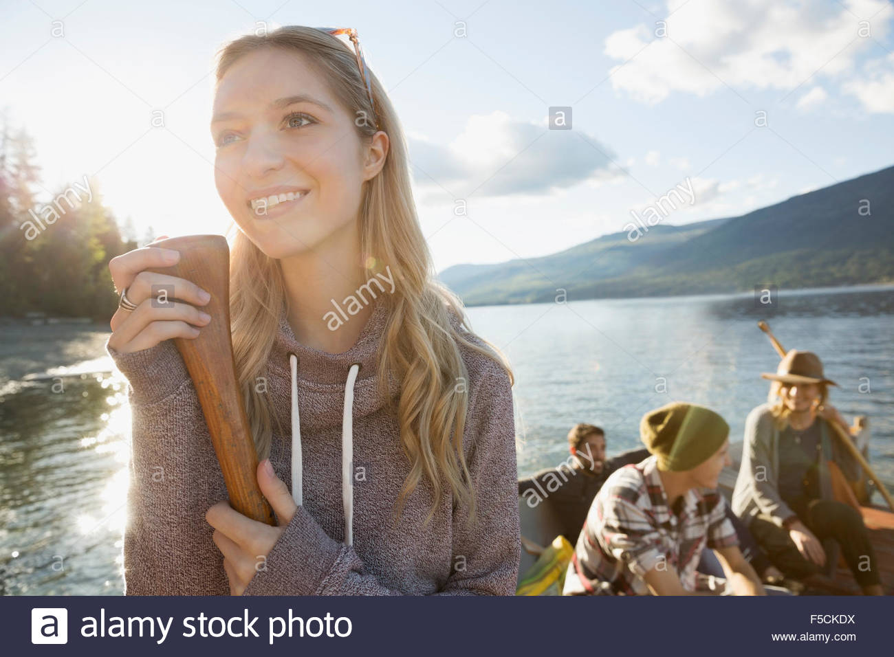 Smiling young woman at lakeside with friends Stock Photo - Alamy