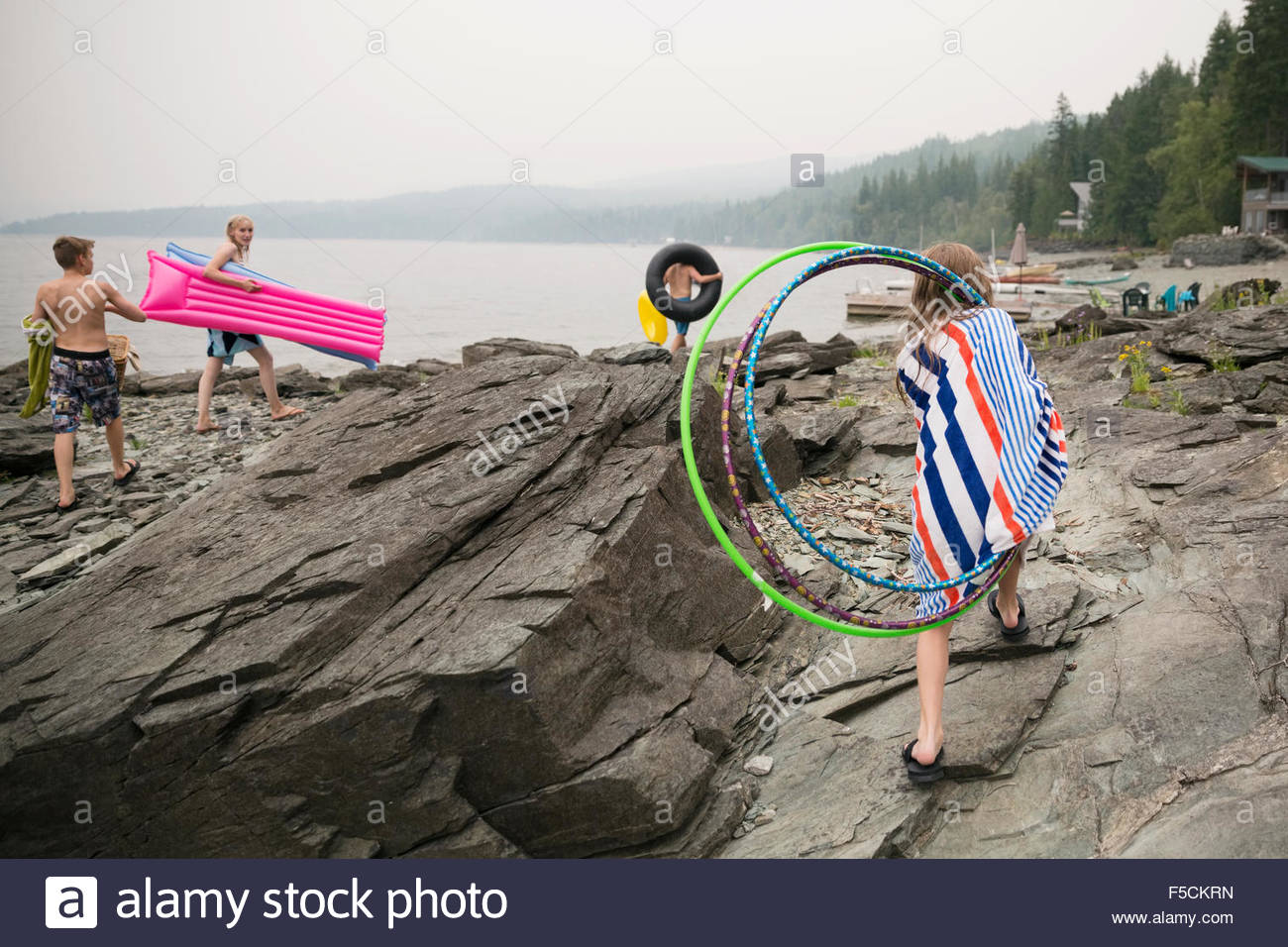 Family with pool rafts plastic hoops rocks lakeside Stock Photo - Alamy