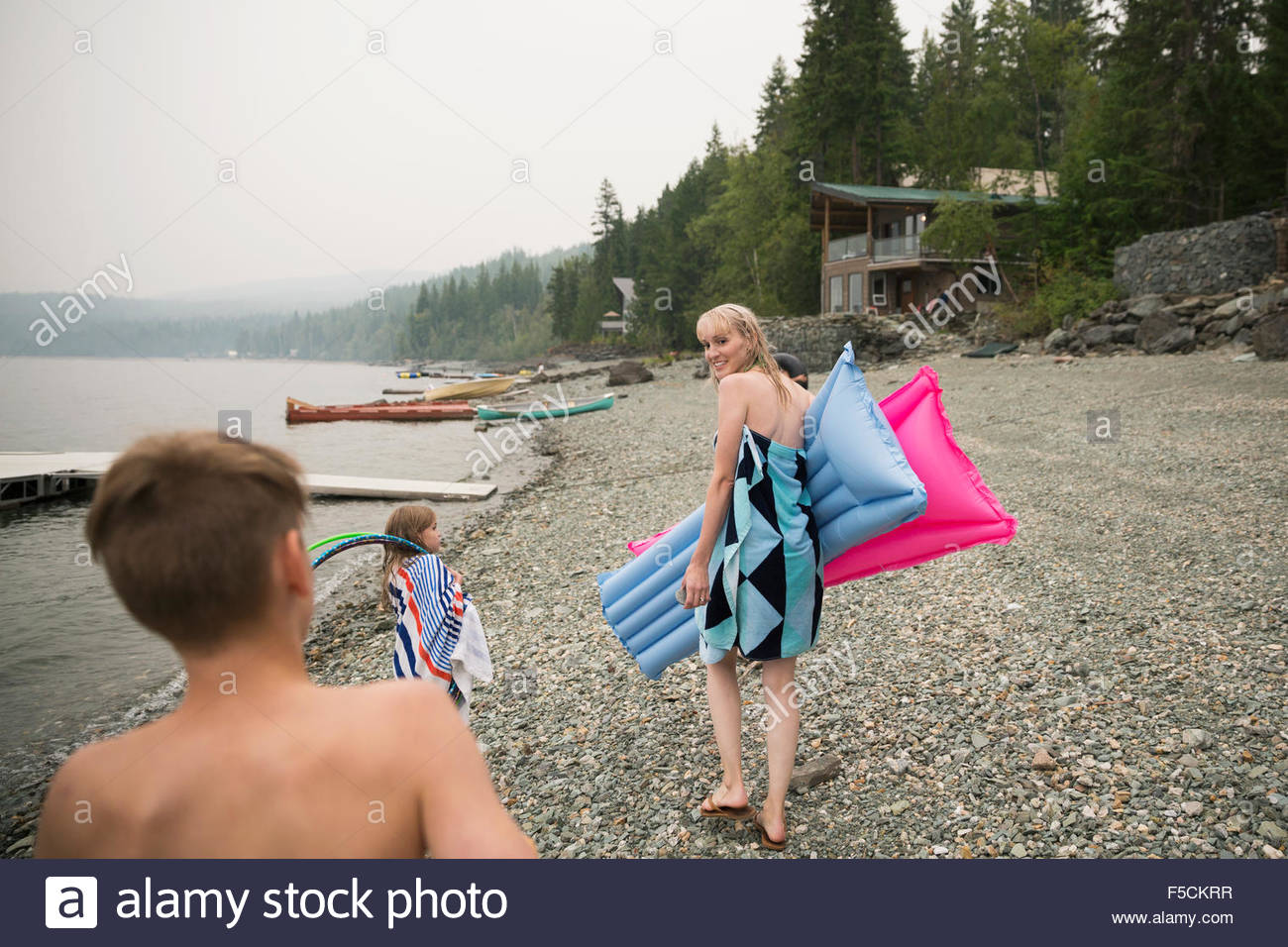 Family carrying pool rafts on lakeside beach Stock Photo - Alamy