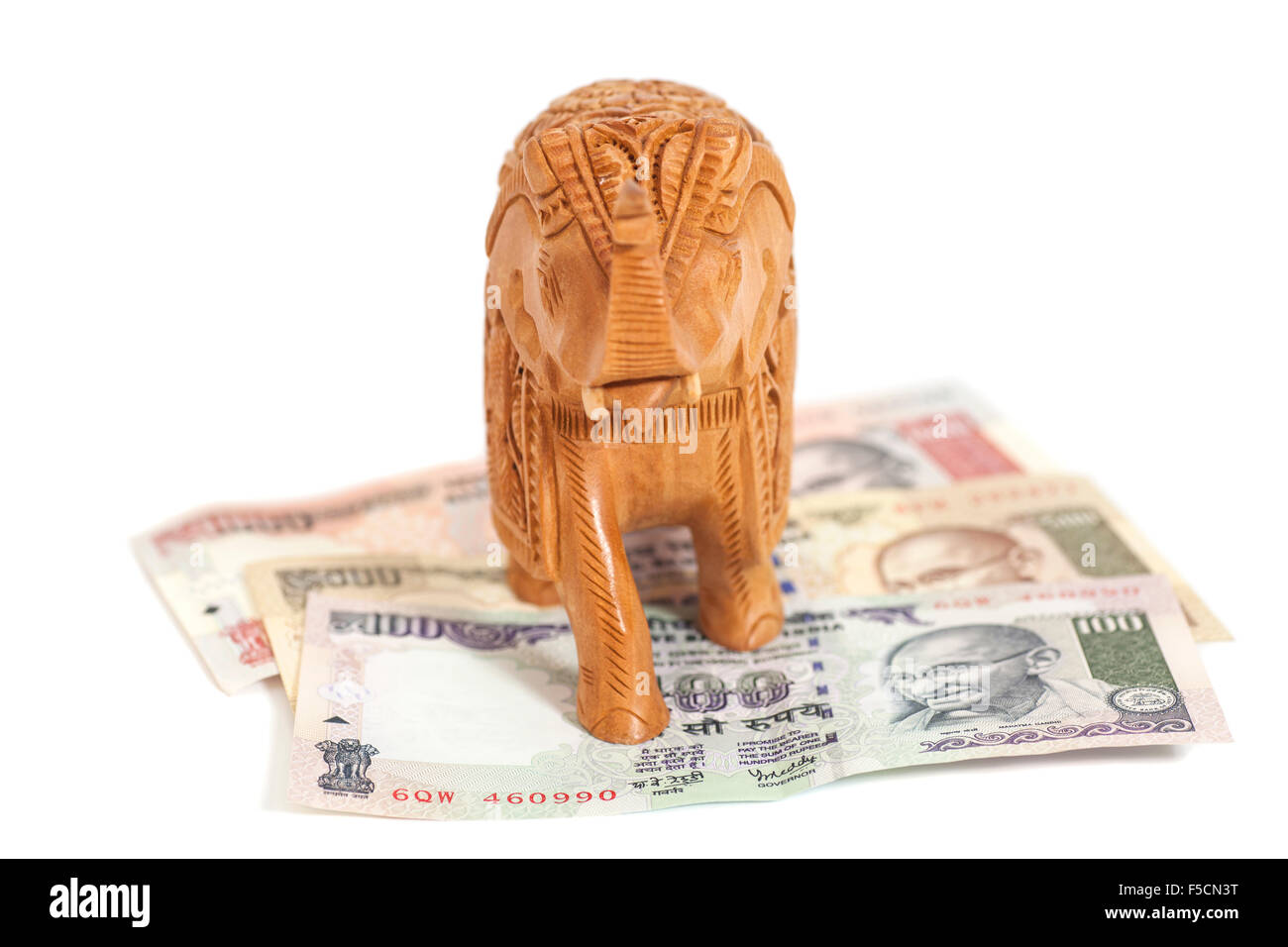 Wooden elephant sculpture on Indian Rupee banknotes isolated on white ...