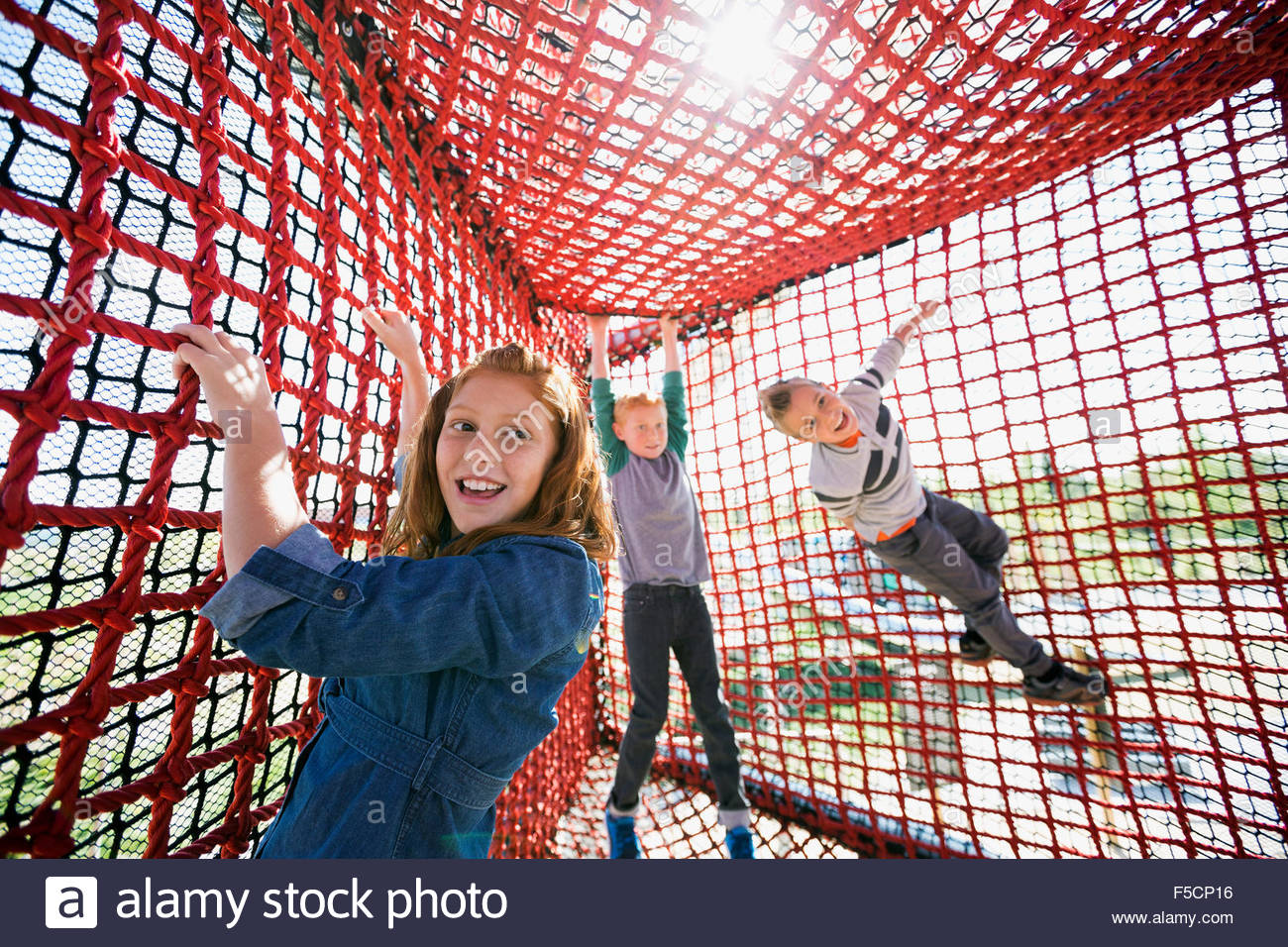Kids playing and climbing rope net sunny playground Stock Photo - Alamy