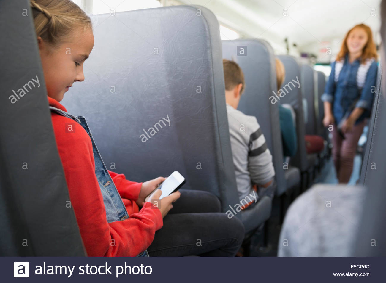 School girl texting with cell phone school bus Stock Photo - Alamy