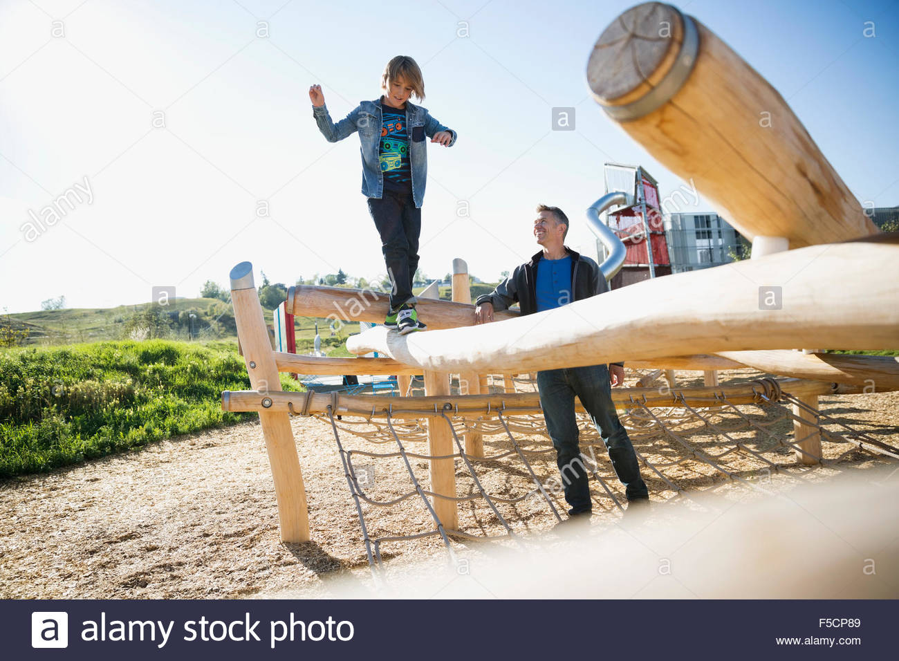 Father watching son balancing logs sunny playground Stock Photo - Alamy