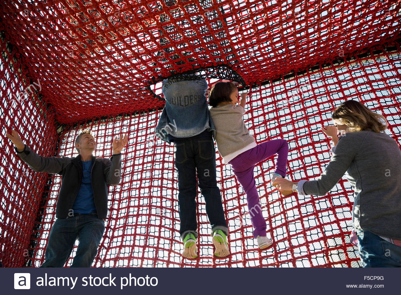 Family climbing rope net at playground Stock Photo - Alamy