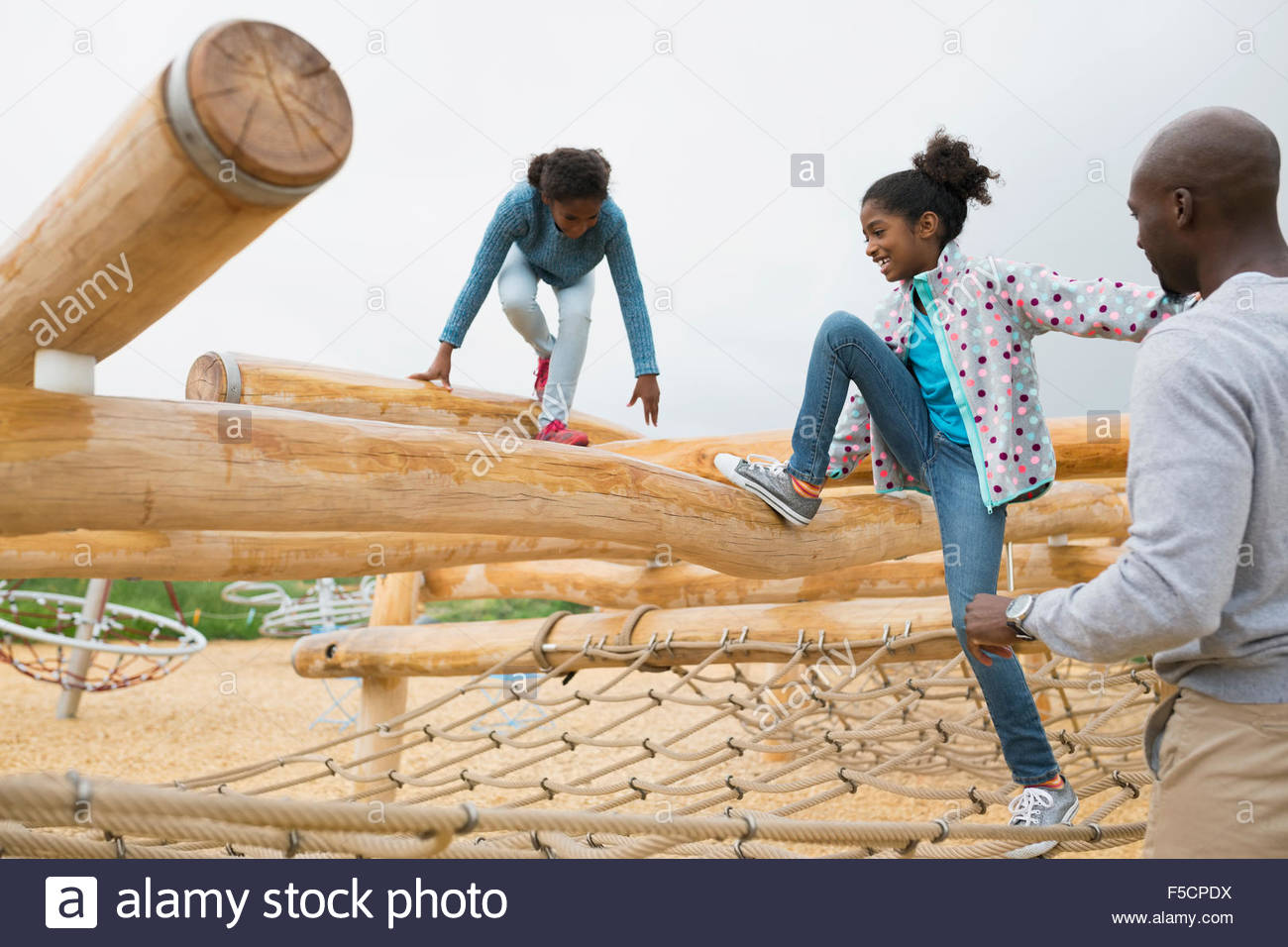 Father helping daughter climb logs at playground Stock Photo - Alamy