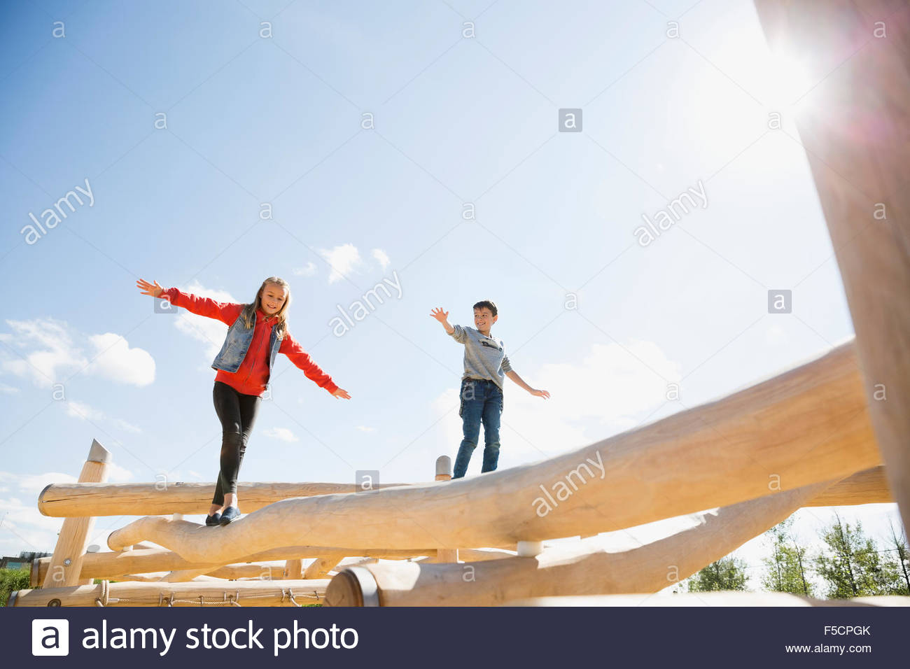 Boy and girl balancing logs sunny playground Stock Photo - Alamy