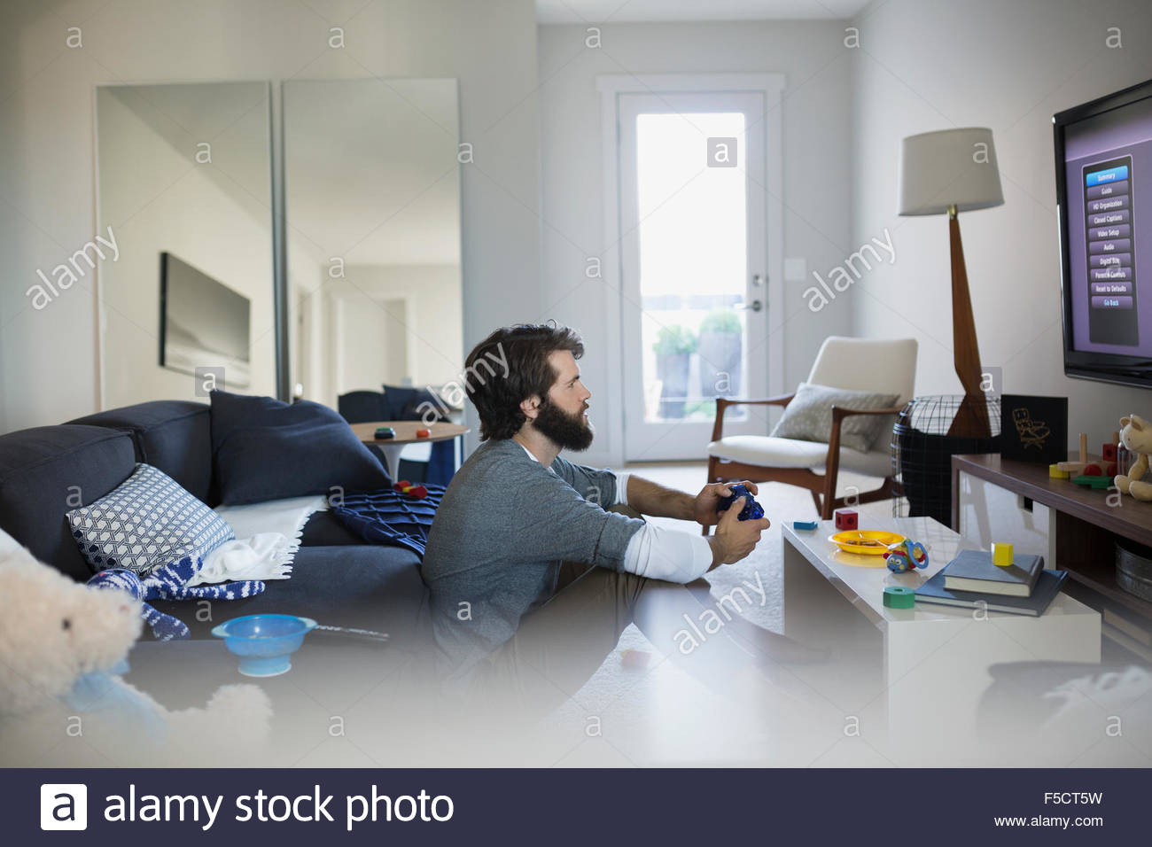 Man playing video game in living room Stock Photo - Alamy