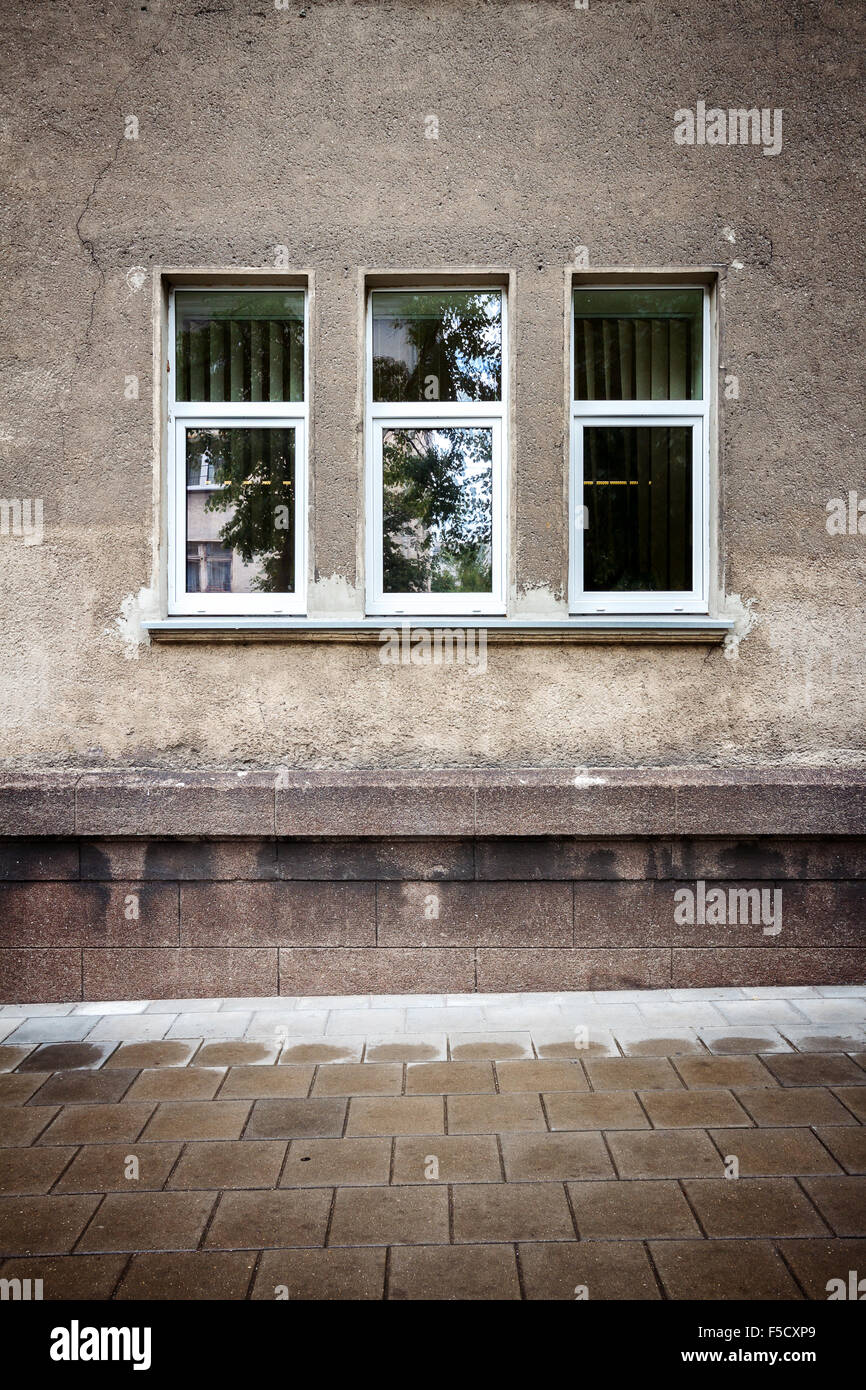 Aged weathered street wall with three windows Stock Photo - Alamy