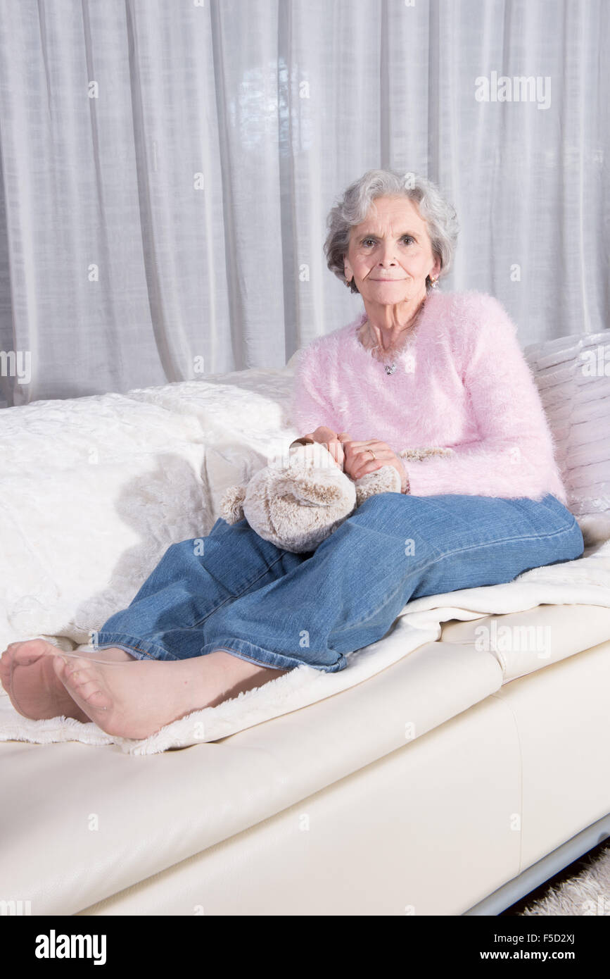 active female senior stretching on couch Stock Photo - Alamy