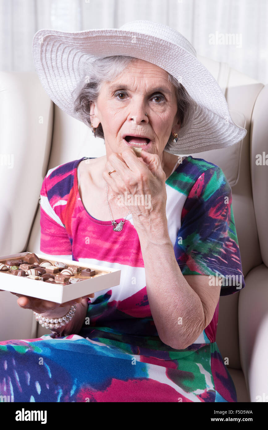 active female senior earing chocolate candy Stock Photo - Alamy