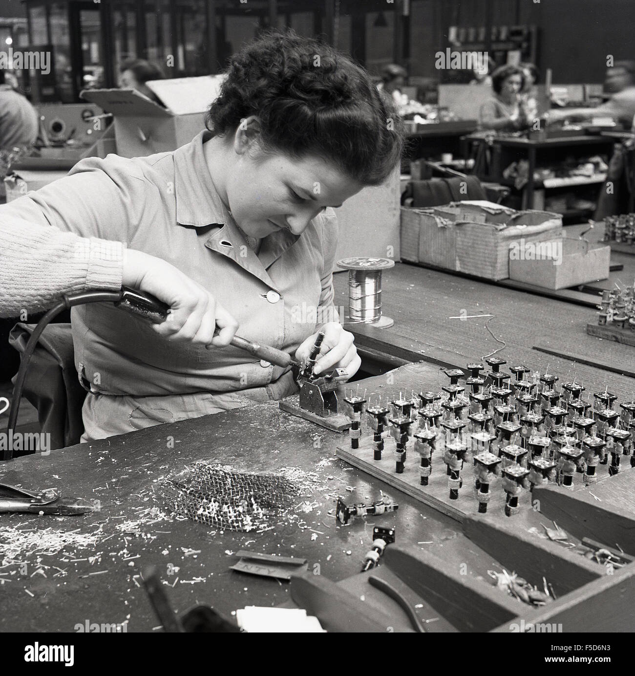 1950s historical, female factory worker using soldering machine tool at ...