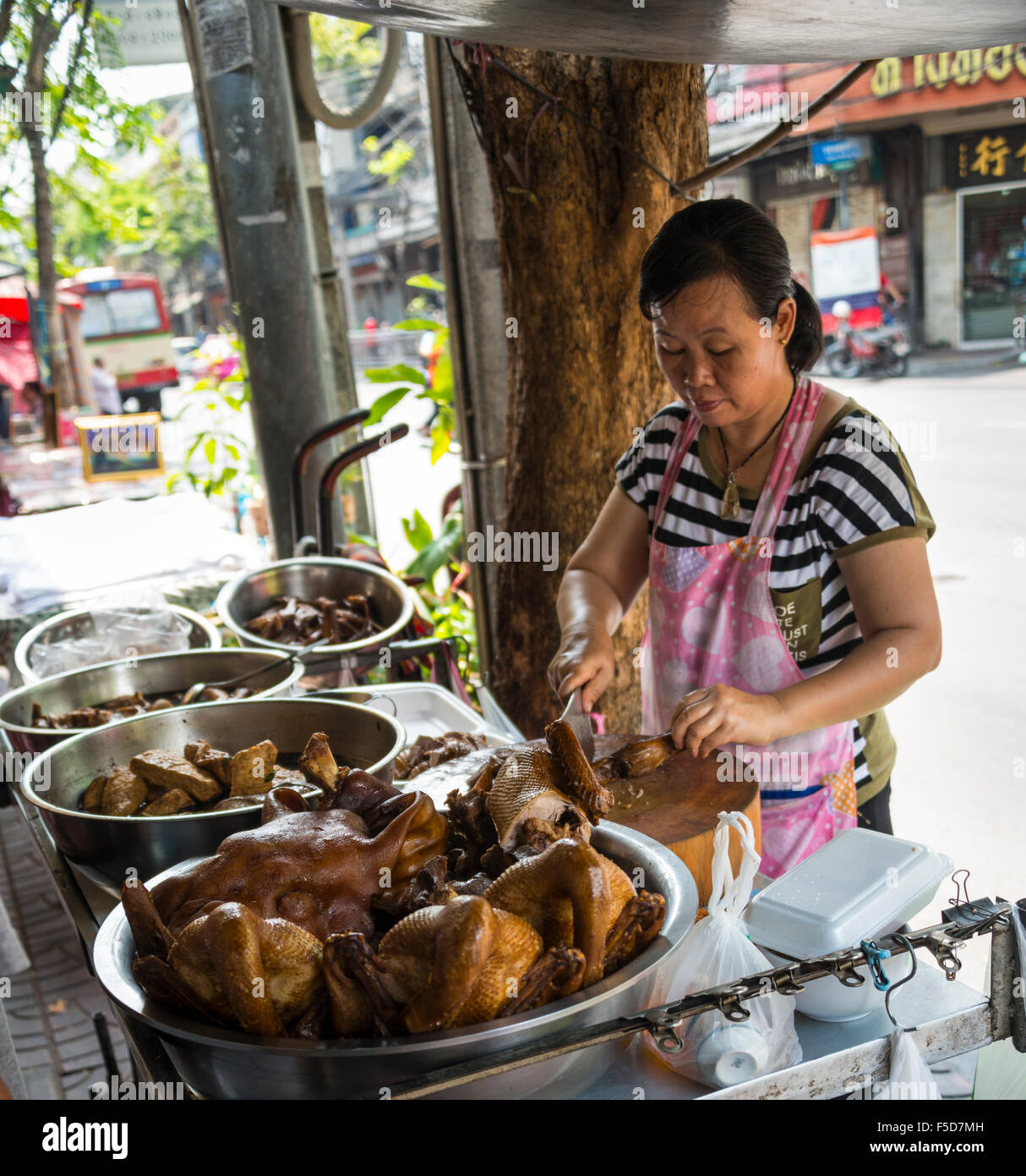 Street vendor preparing chicken at food stall, Chinatown, Bangkok ...
