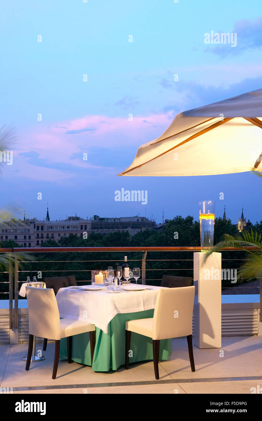 Dinner table for two on the roof in Madrid view background at evening ...