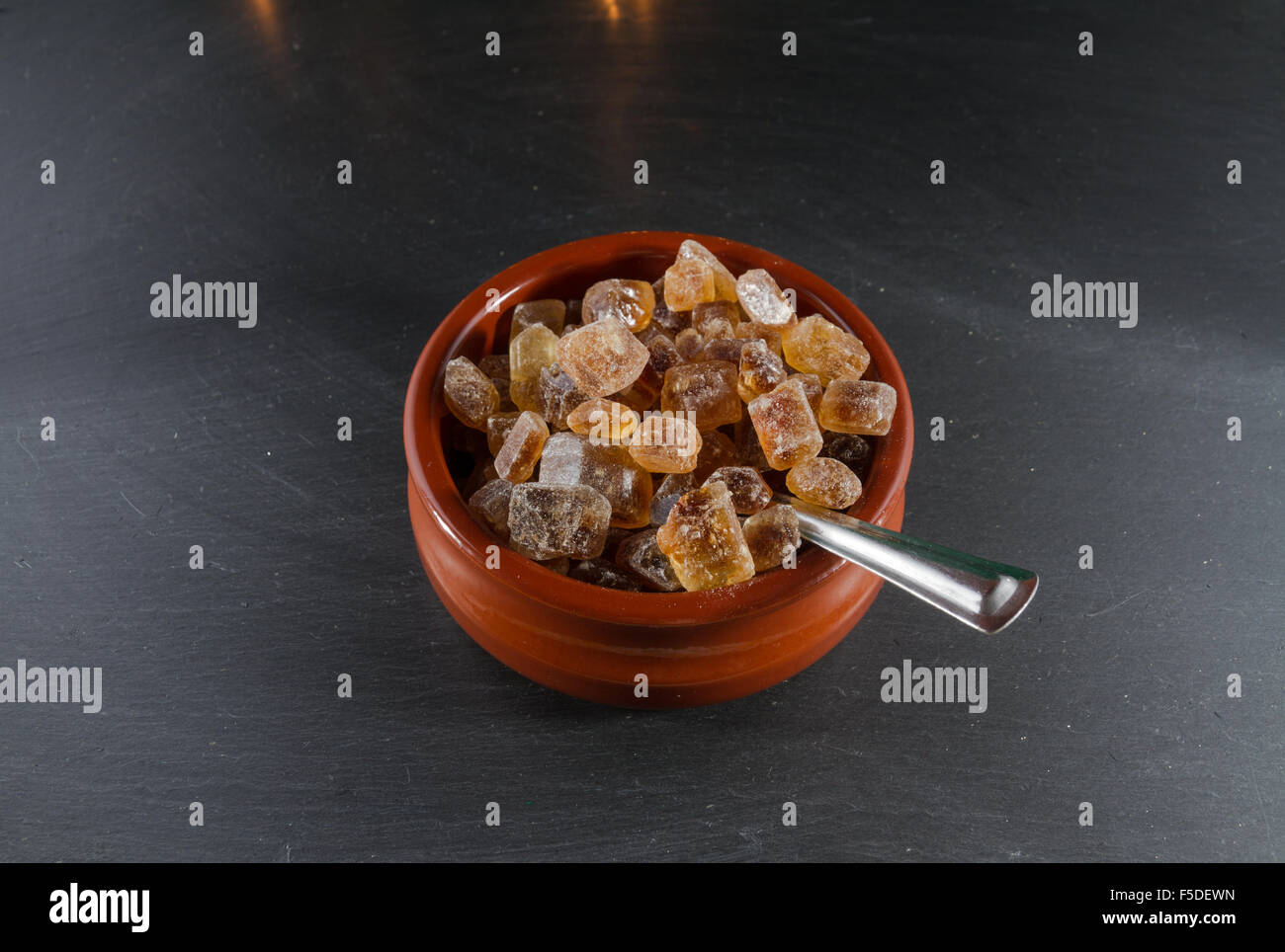 Macro of German Rock Sugar, brauner Kandis in a terracotta brown bowl ...