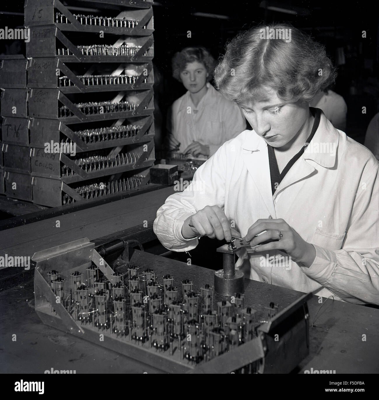 1950s historical, female operative wearing white overall works on a ...