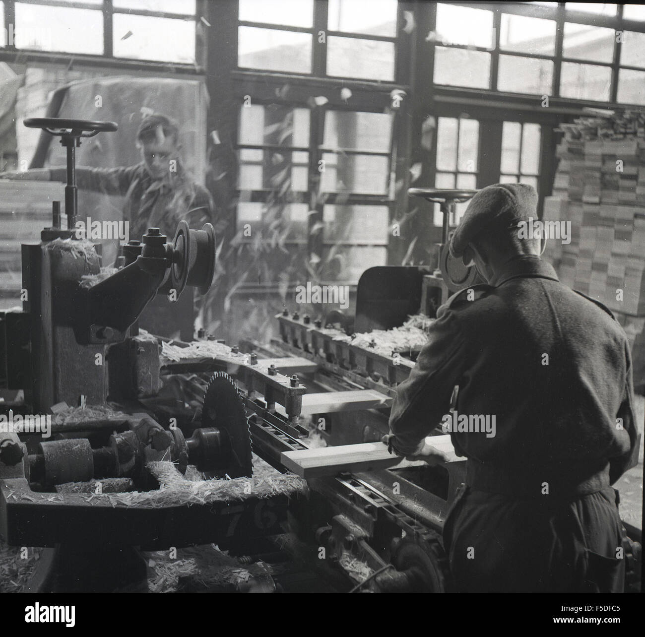 1950s historical, male operators in factory, one in army uniform, using ...