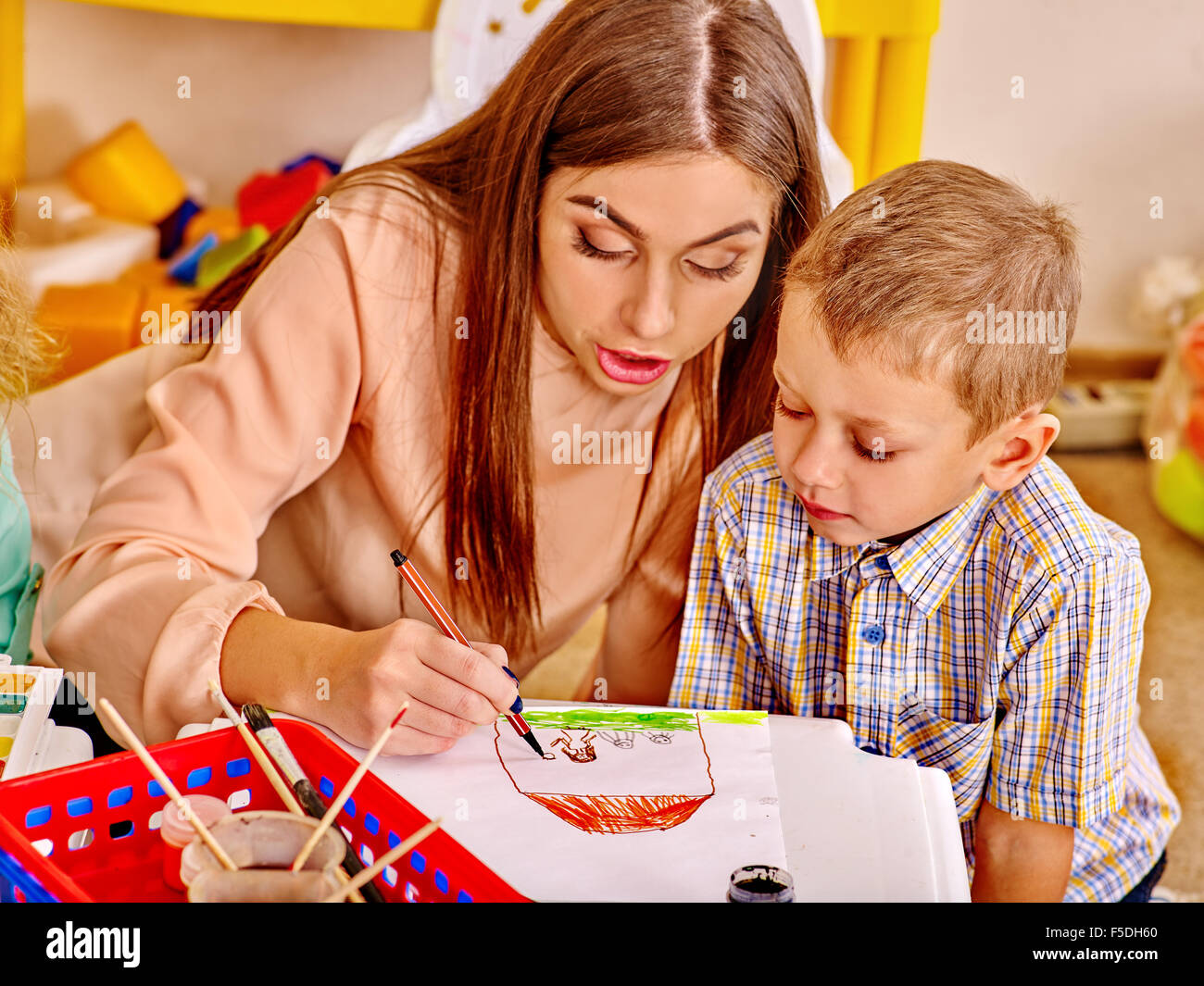 Woman with kids holding colored paper and glue in kindergarten Stock ... Woman with kids holding colored paper and glue in kindergarten Stock ...