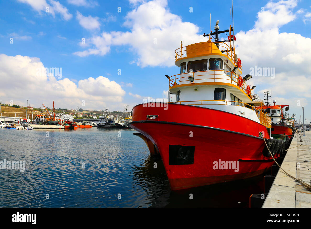 Red colored fishing boat in a commercial harbor and a blue sky Stock ...