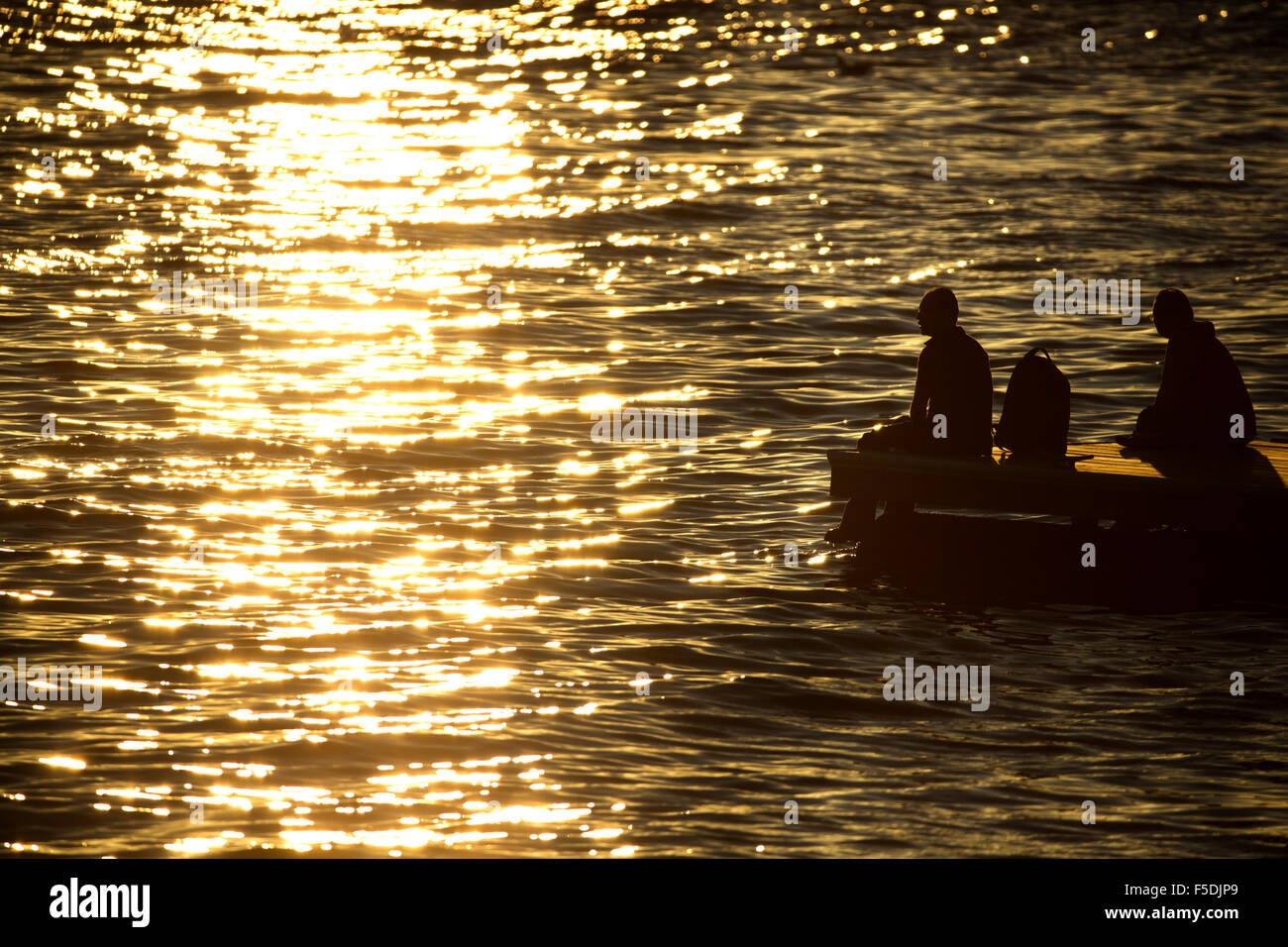 people sitting on a dock during sunset on Boston Harbor Stock Photo - Alamy