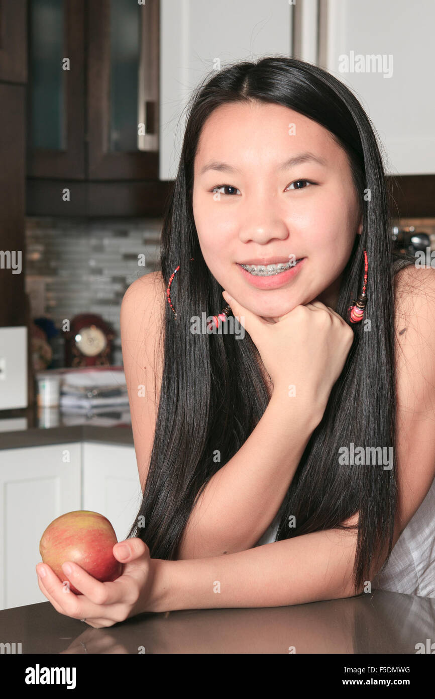 smiling teenager girl with apple in kitchen Stock Photo - Alamy