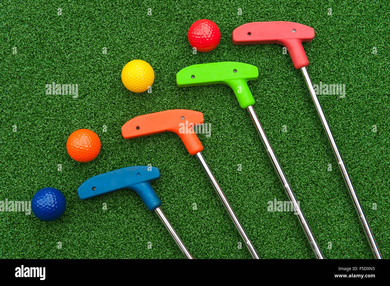 Four mini golf putters and balls of assorted colors Stock Photo - Alamy