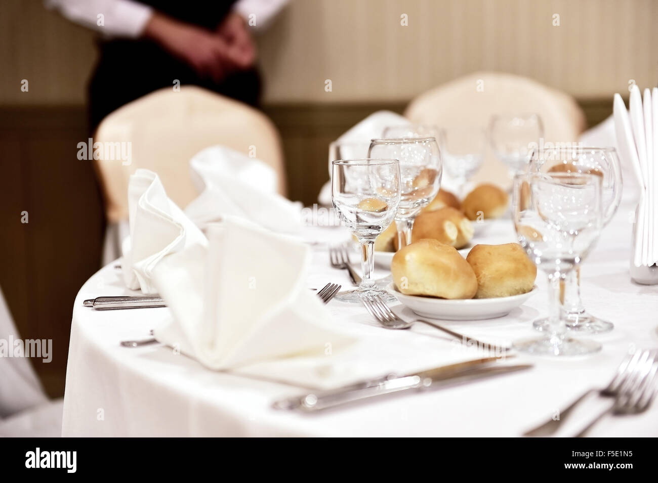 Cutlery detail shot on an elegant restaurant table with a waiter in ...