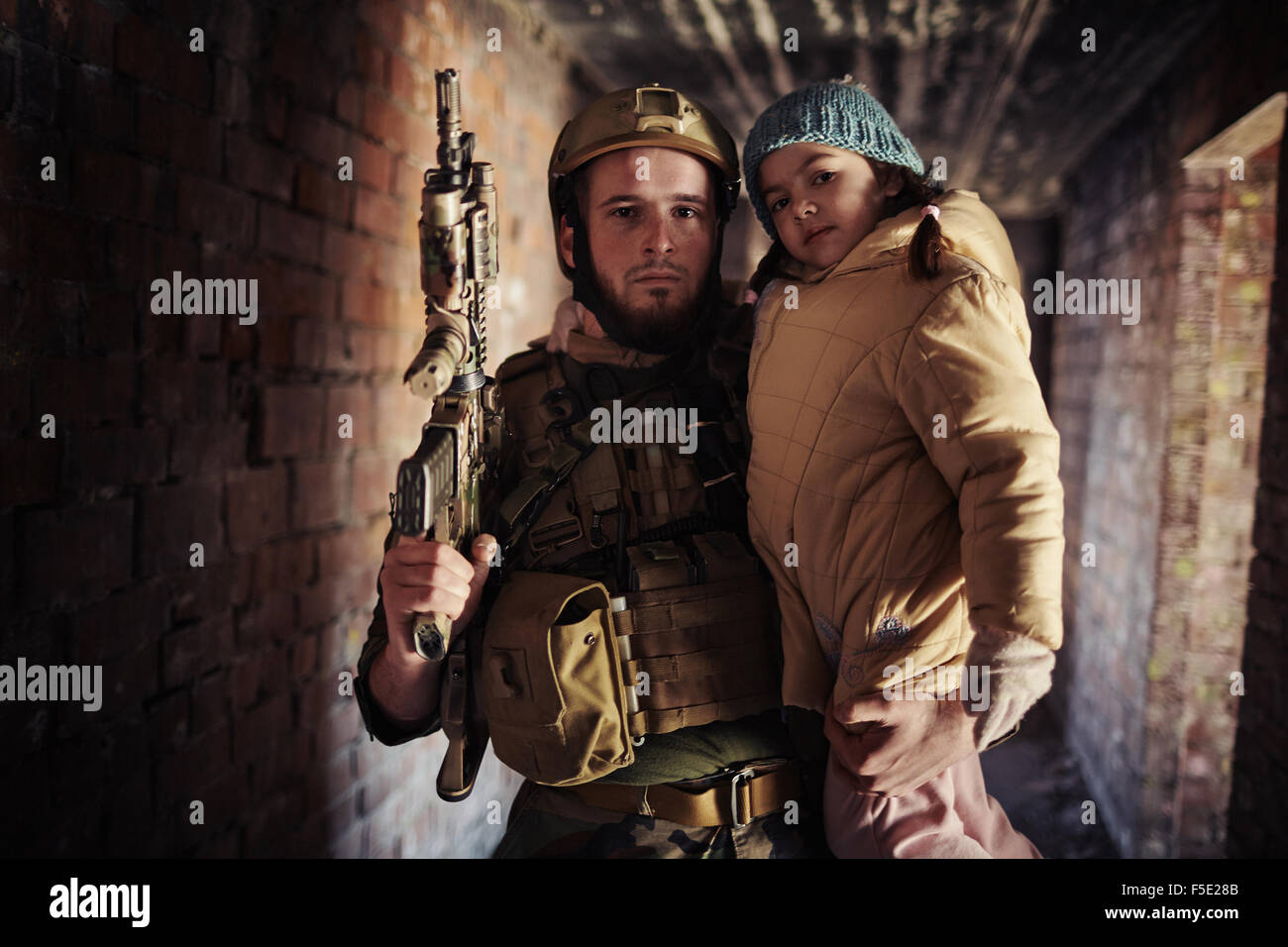 Young warrior with gun holding little girl Stock Photo - Alamy