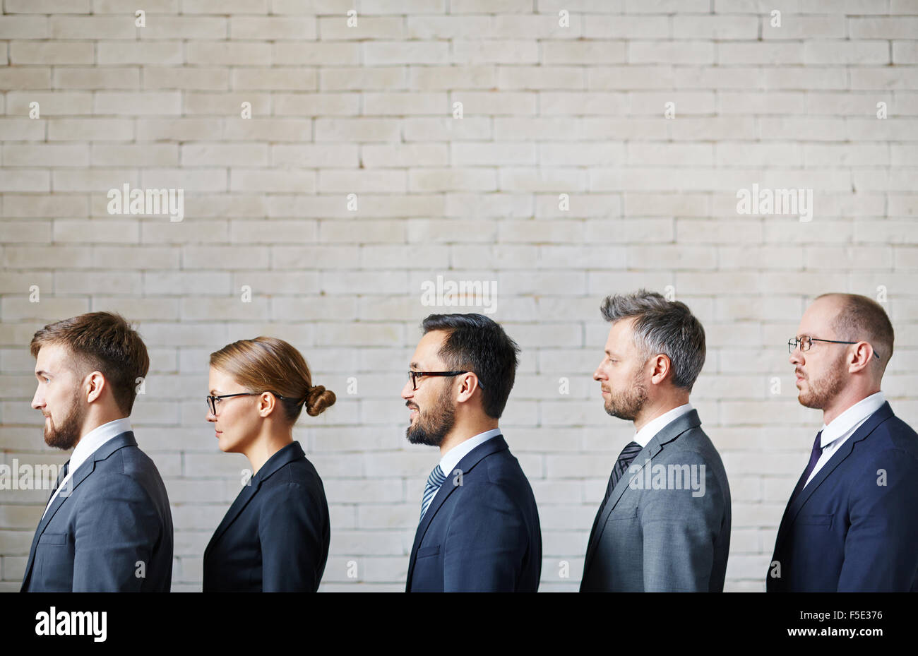 Several employees standing in queue along wall Stock Photo - Alamy