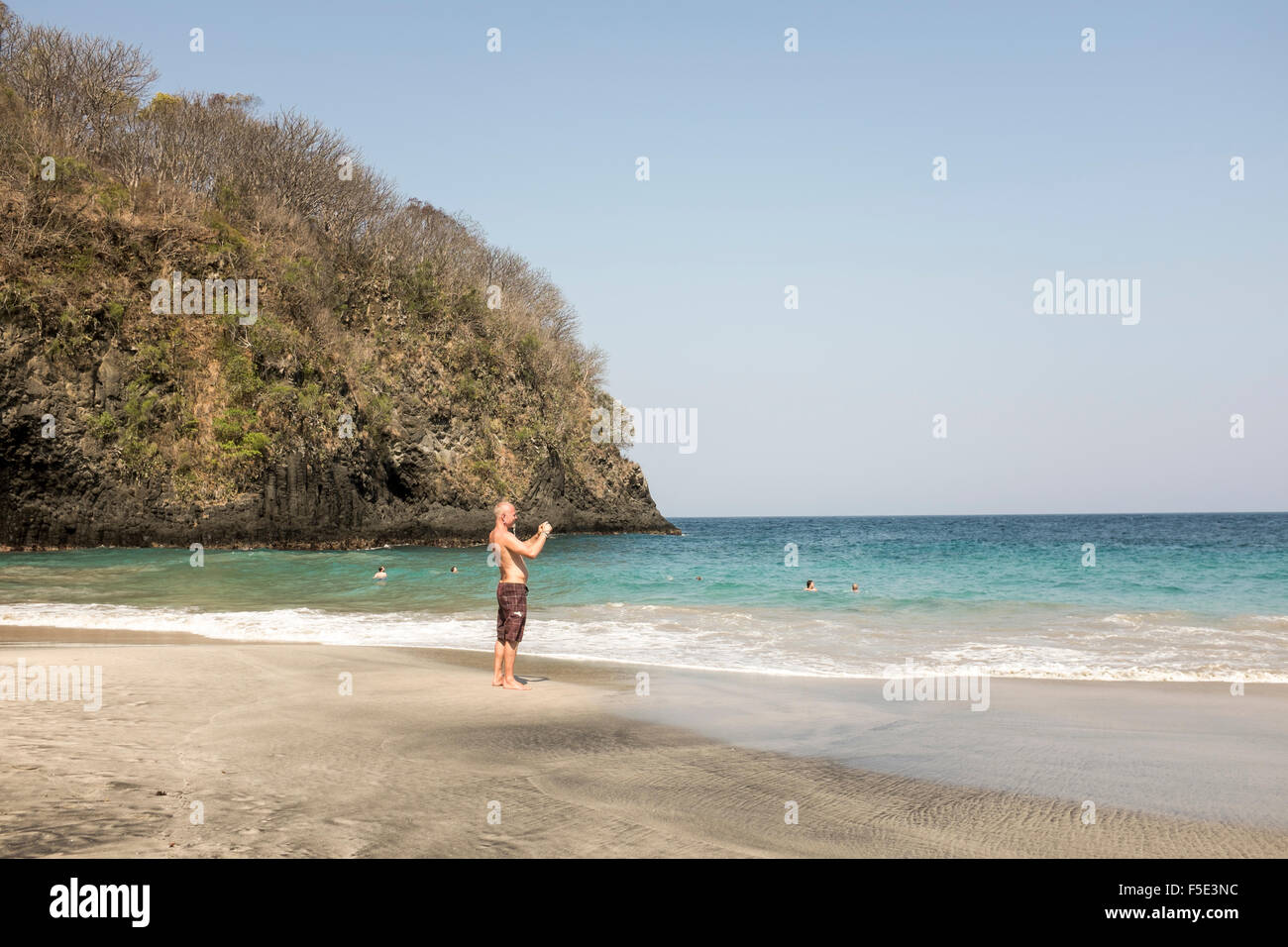 A man takes photos at Pasir Putih, or White Sand beach, in Bali ...