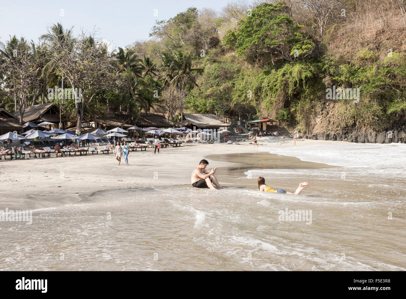 A couple take photos at Pasir Putih, or White Sand beach, in Bali ...