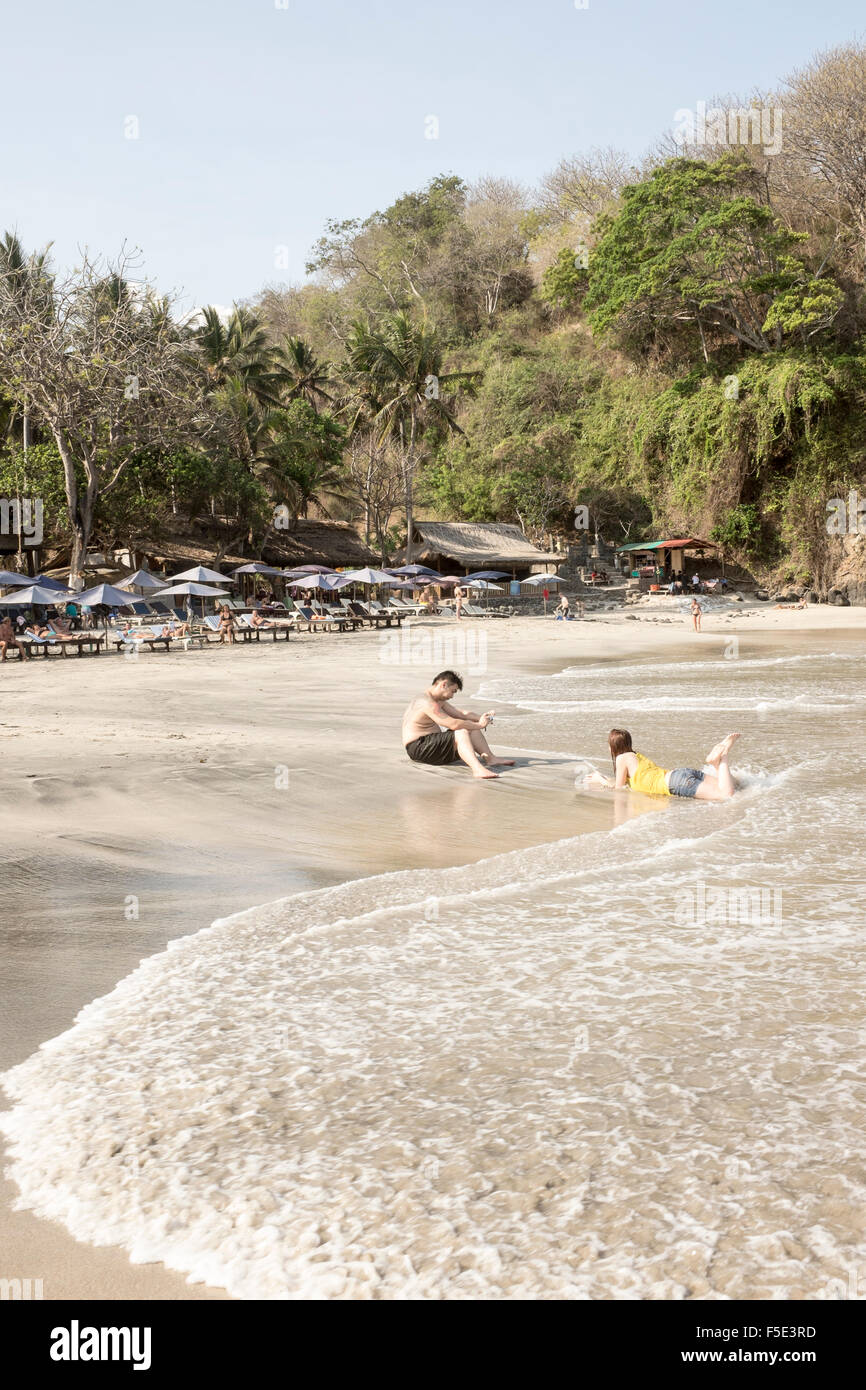 A couple take photos at Pasir Putih, or White Sand beach, in Bali ...